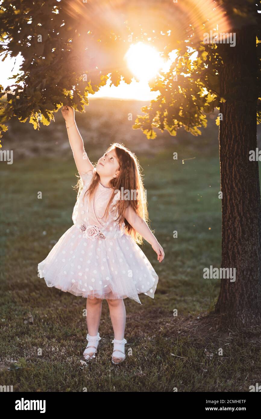 Happy ginger girl plays in the park, holds onto tree branch Stock Photo ...
