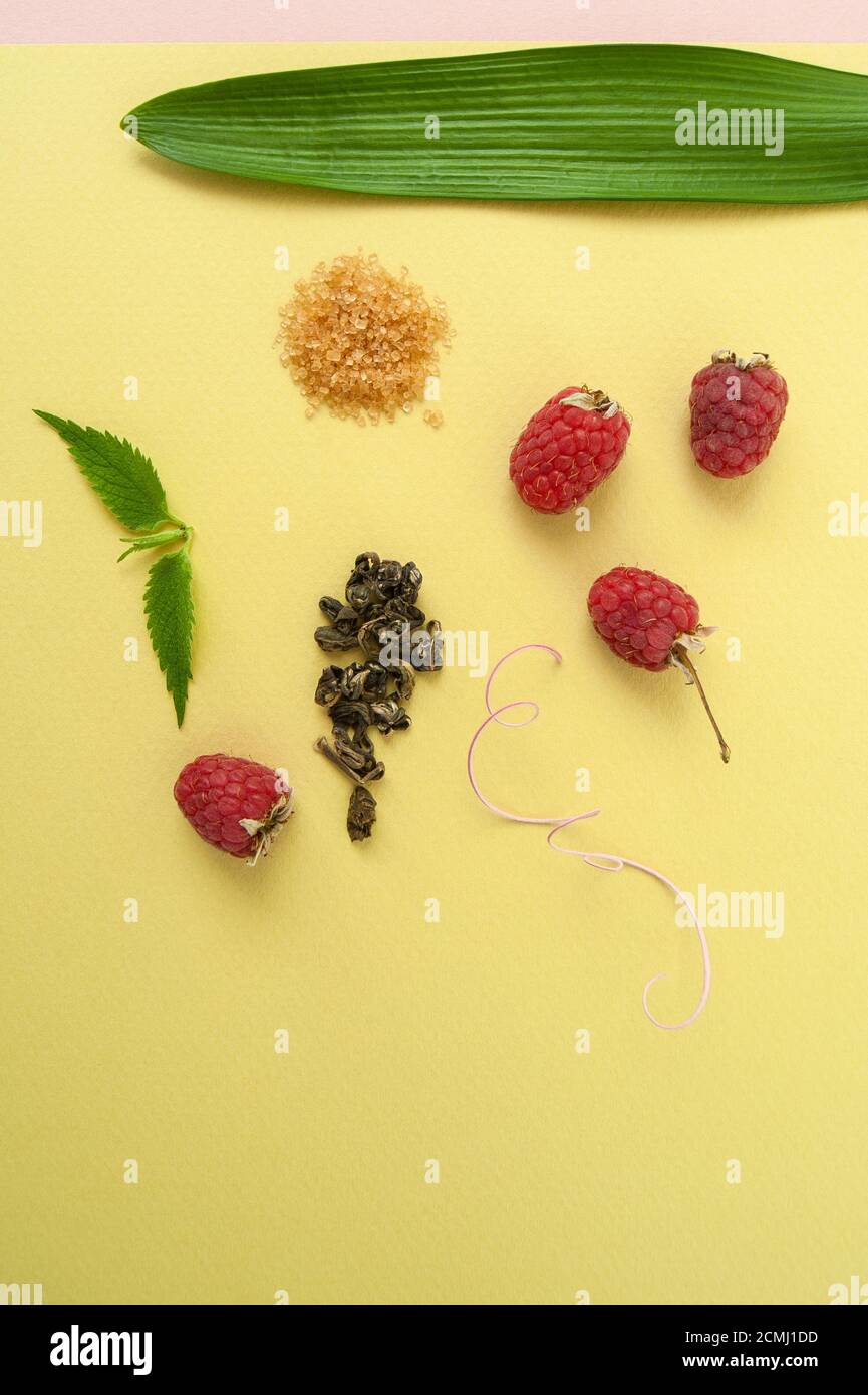 Ripe raspberries, sugar, mint leaves and a scattering of green tea on a ...