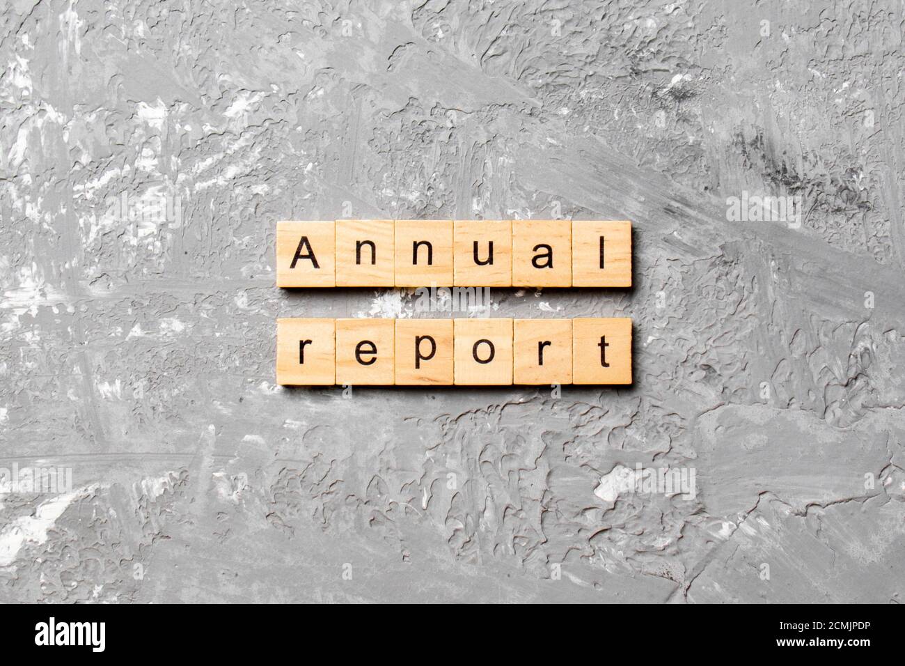 Annual report word written on wood block. Annual report text on cement ...