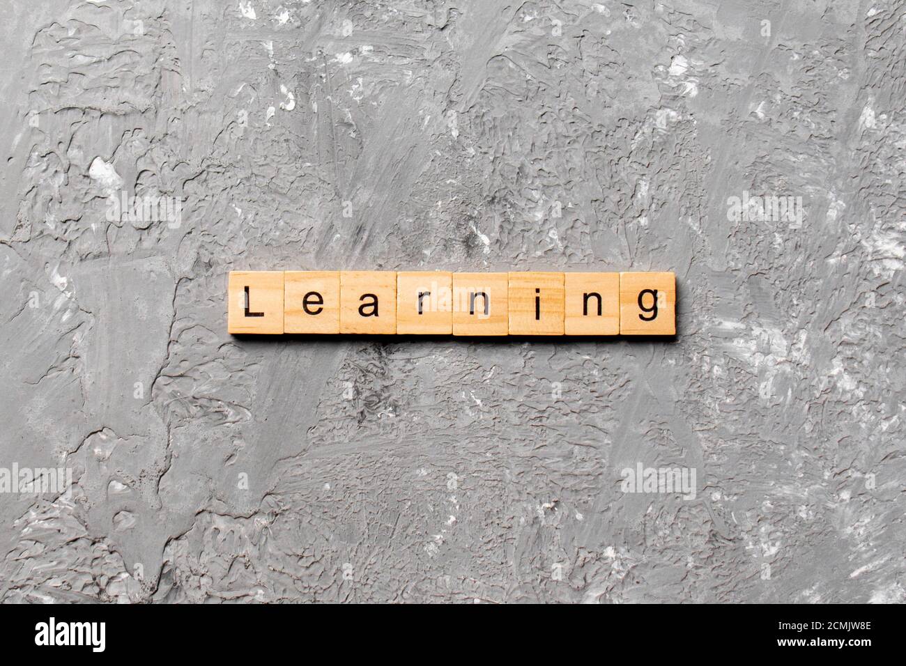 LEARNING word written on wood block. LEARNING text on cement table for ...