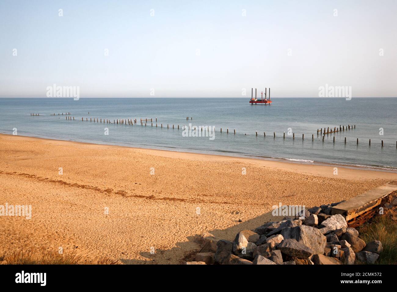 A view of derelict breakwater and groyne timber posts with small ...