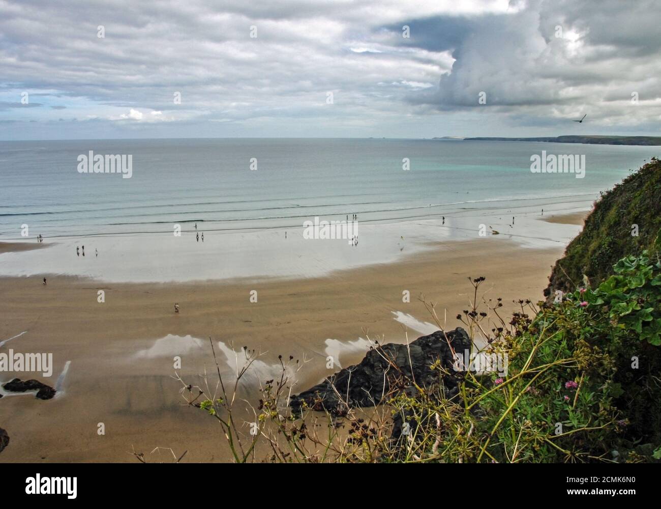 The sea is calm and the beach sparcely populated but rain clouds are on ...