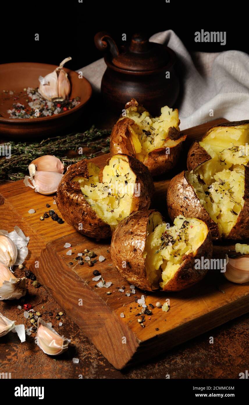 broken baked potato with spices and herbs on a wooden board Stock Photo ...