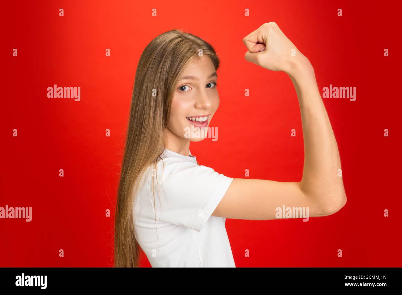 Power, strong. Portrait of young caucasian woman on red studio ...