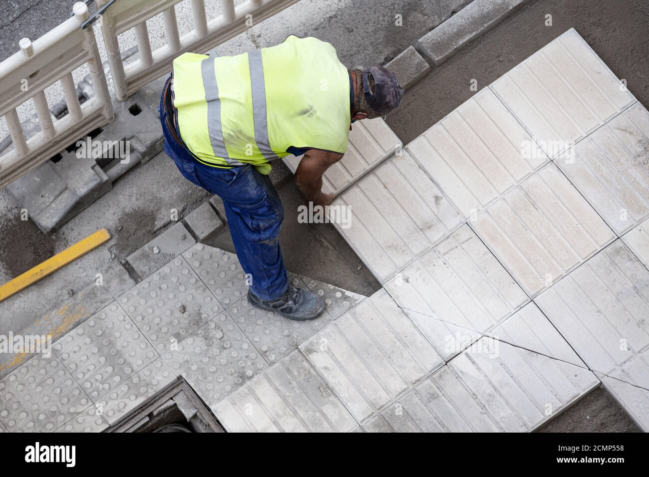 Construction worker laying a tile repairing a sidewalk. Maintenance ...
