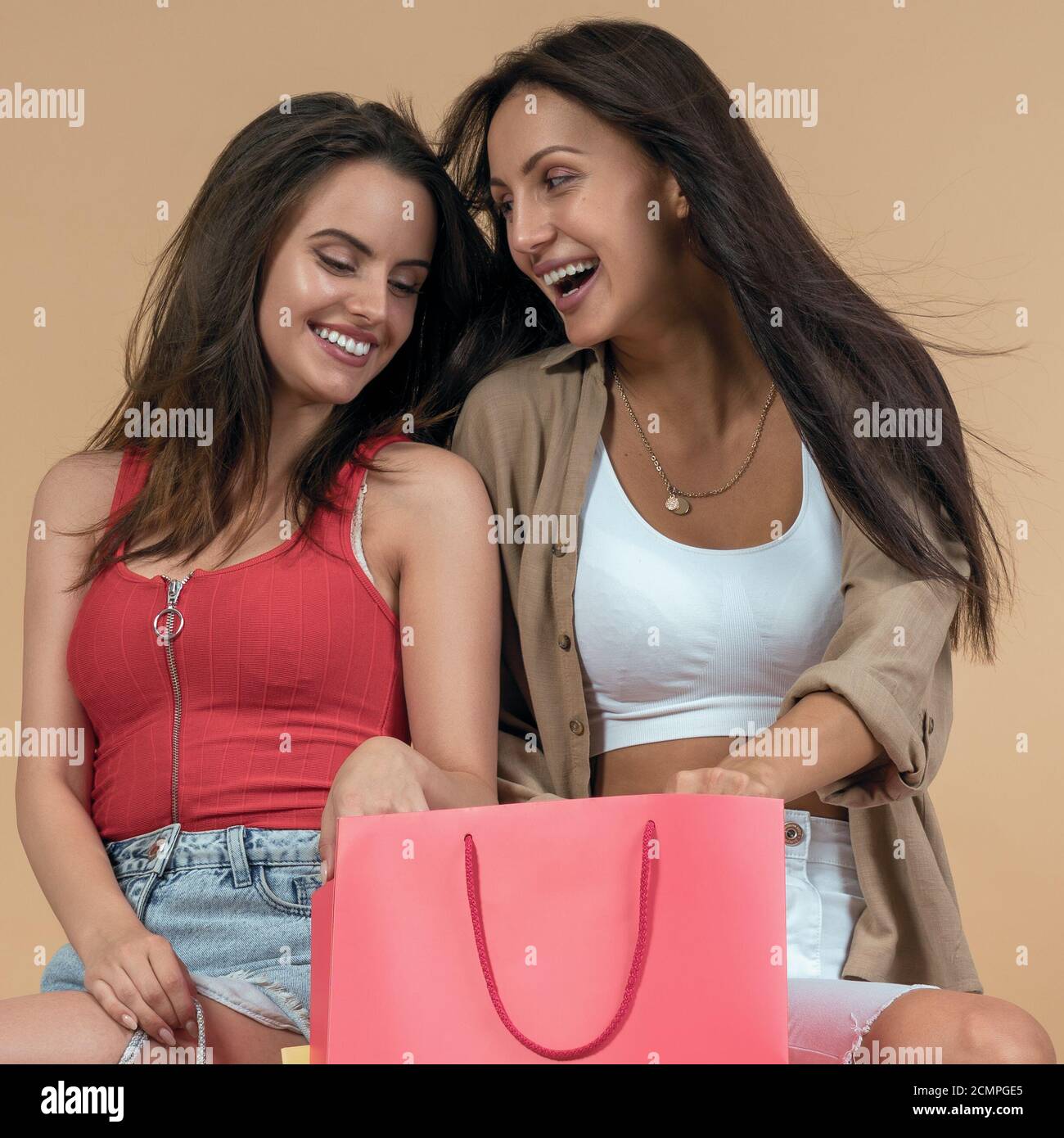 Two young women holding a shopping bag and laughing Stock Photo - Alamy