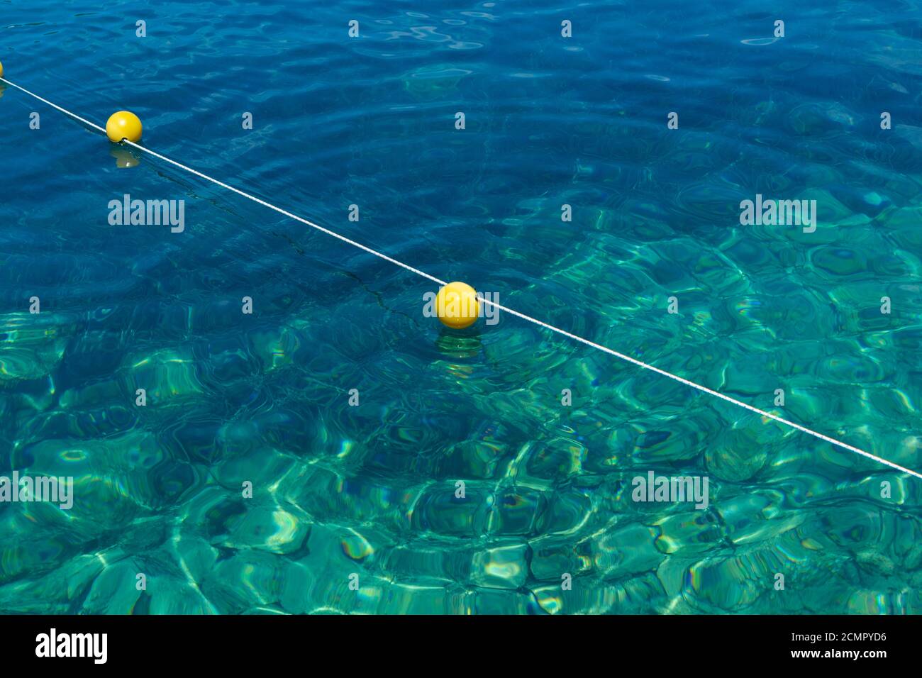 Rope with yellow plastic balls on the sea water surface showing the end ...