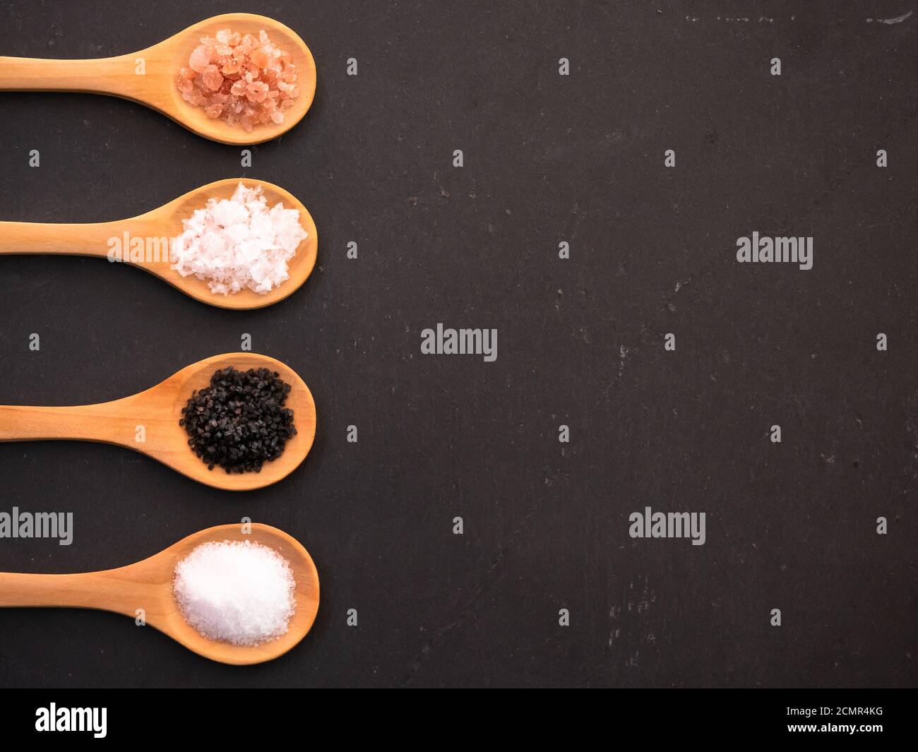 Wooden spoons with himalayan salt, black hawaii salt, common salt and ...
