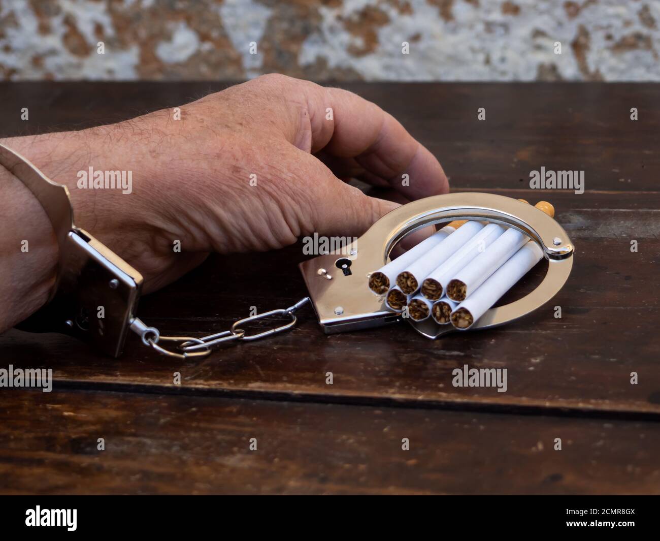 A man handcuffed to a handful of cigarettes. Tobacco addiction concept ...