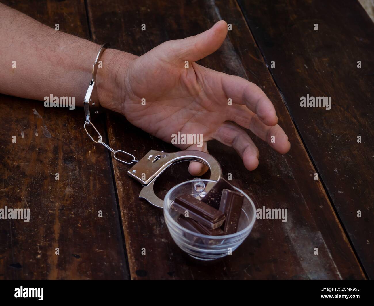 A man handcuffed to a cup with chocolate. Food or chocolate addiction ...