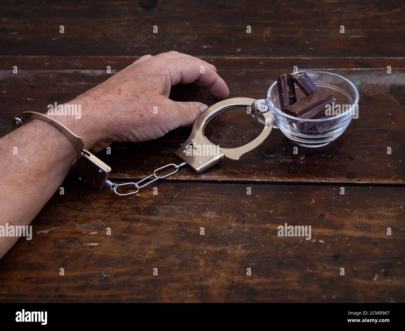 A man handcuffed to a cup with chocolate. Food or chocolate addiction ...