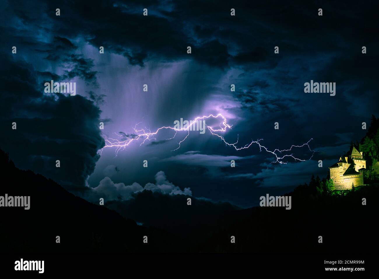 Bolt of lightning cuts through the sky near a castle in the mountains ...
