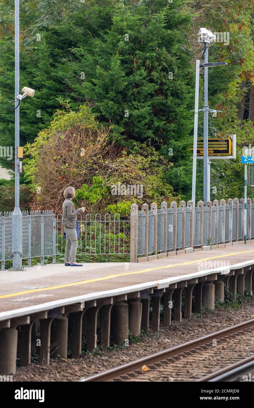 a middle-aged woman waiting for a train on a deserted country railway ...