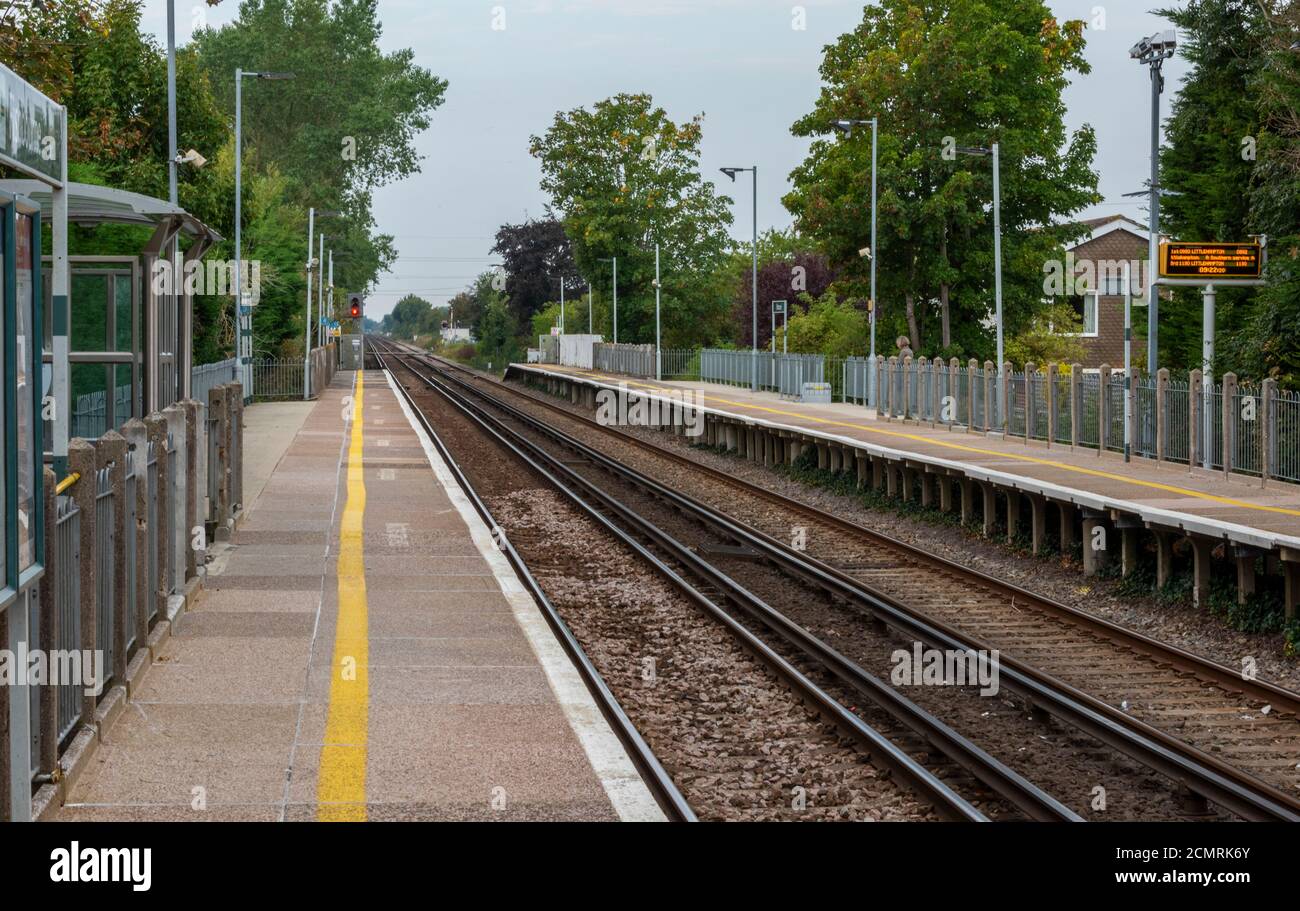 a woman standing alone on a countryside railway station platform ...