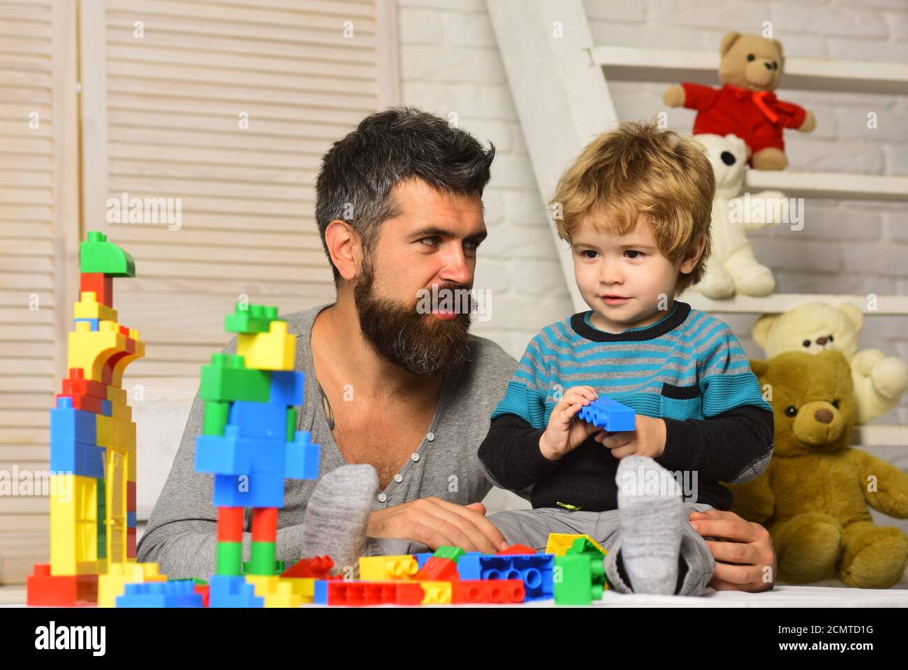 Father and son with smiling faces create colorful constructions with ...