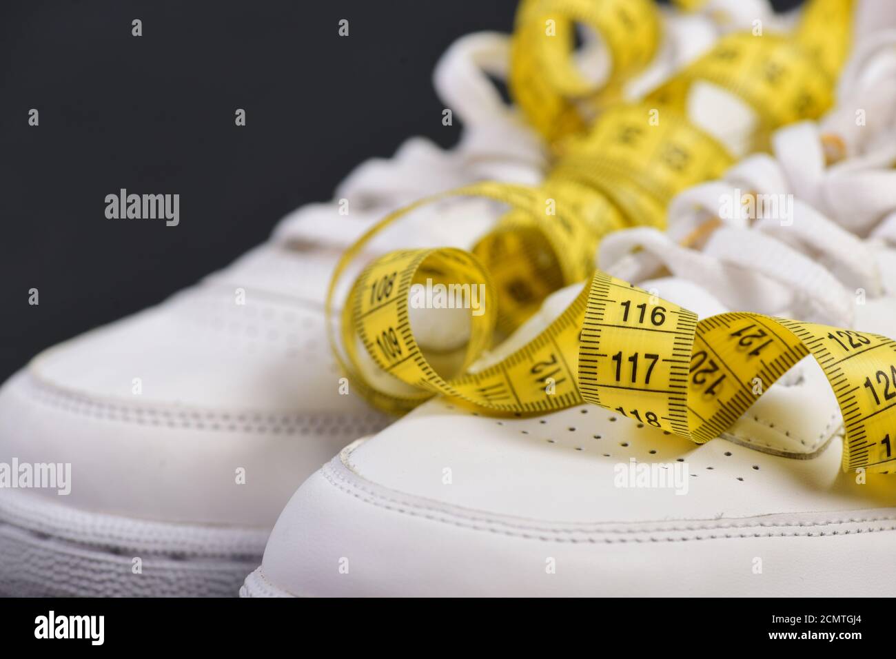 Sneakers with measuring tape on black background. Fitness and ...