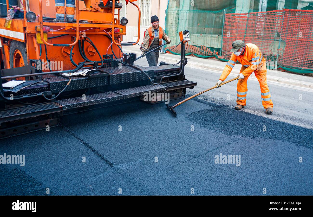Worker regulate tracked paver laying asphalt heated to temperatures ...