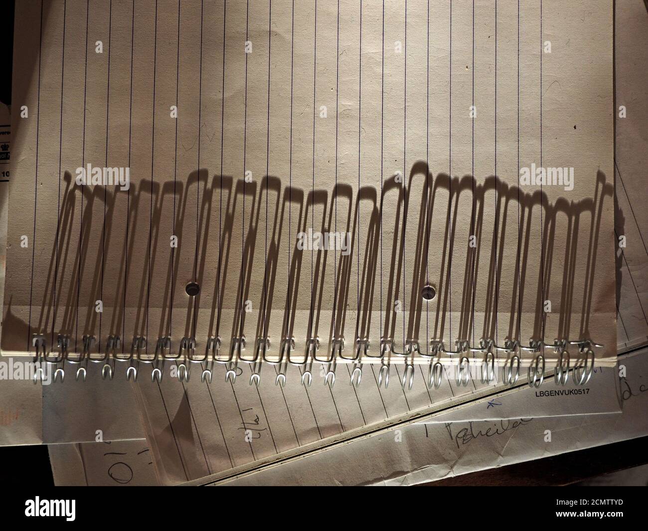 Long shadows from metal loops of ring bound notepad stretch across the ...