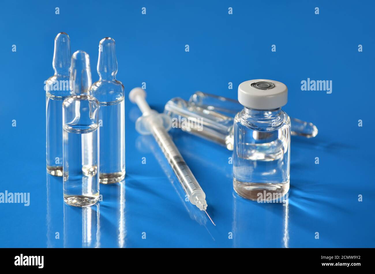 Medical bottle of drug, glass ampoules and a disposable syringe on a ...