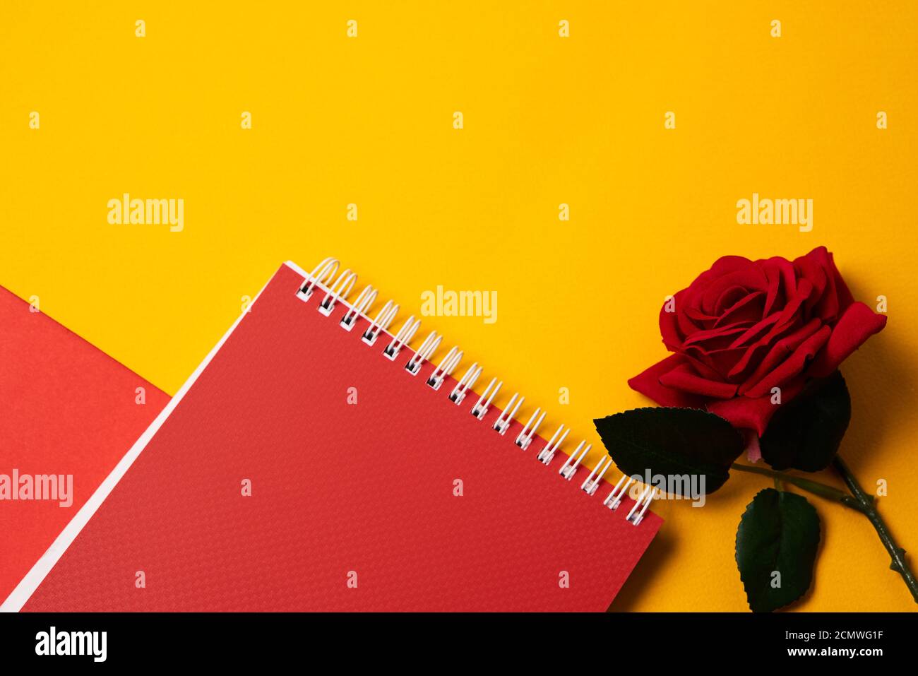 Red notepad and rose on a yellow background cropped top view Stock ...
