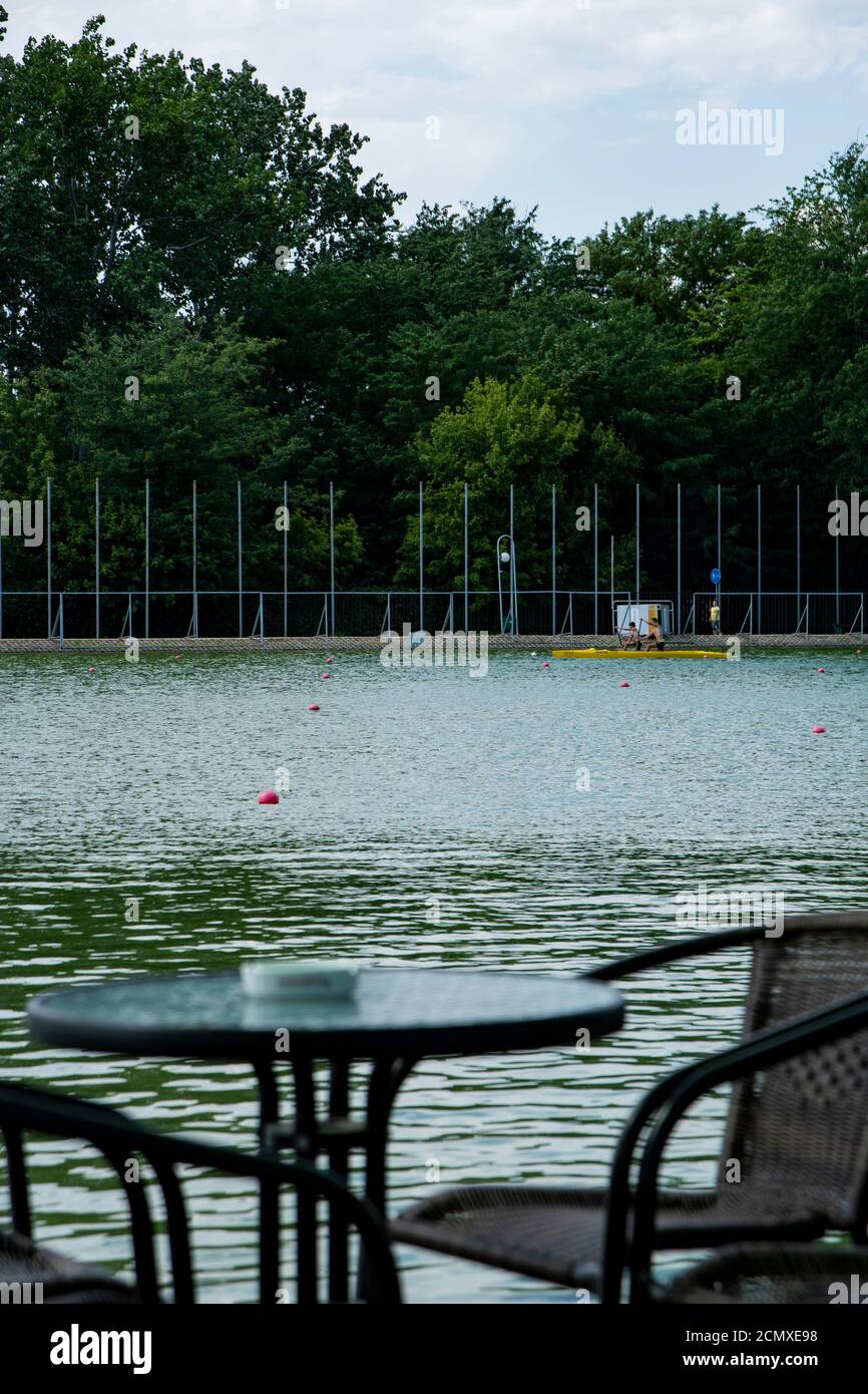 People rowing in the distance on a rowing canal and a coffee table with ...