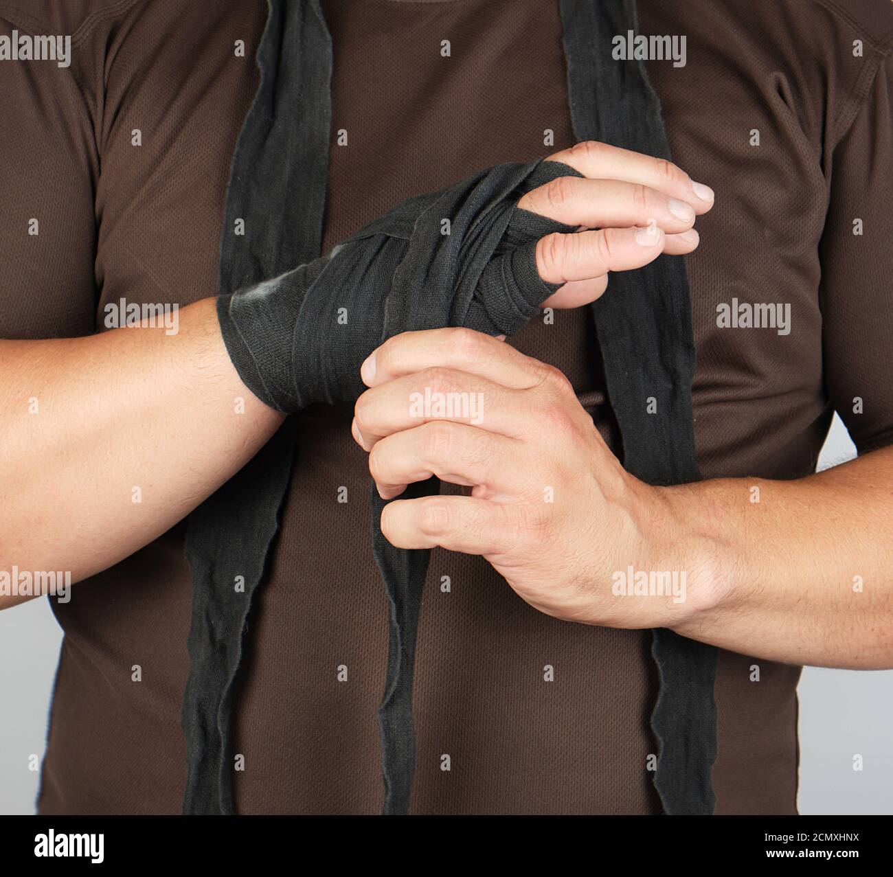 man wraps his hands in black textile bandage for sports, white ...