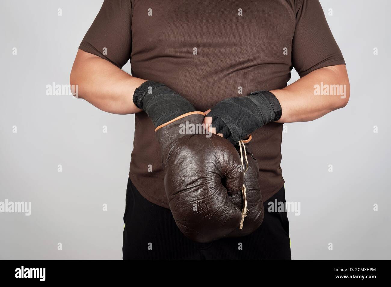 man stands and puts on his hands very old vintage brown boxing gloves ...