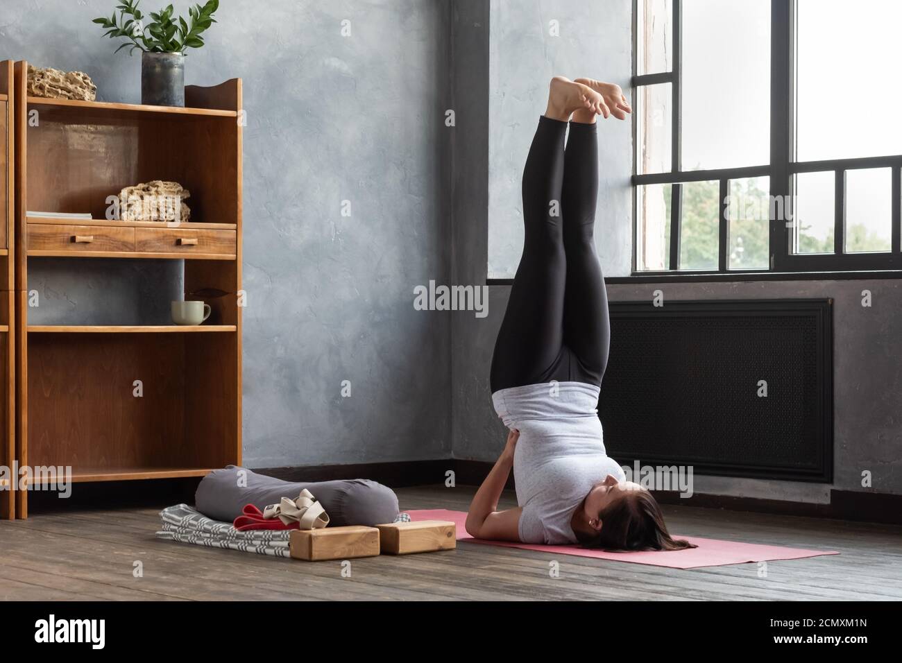 Sporty caucasian woman doing shoulder stand exercise, asana Viparita ...