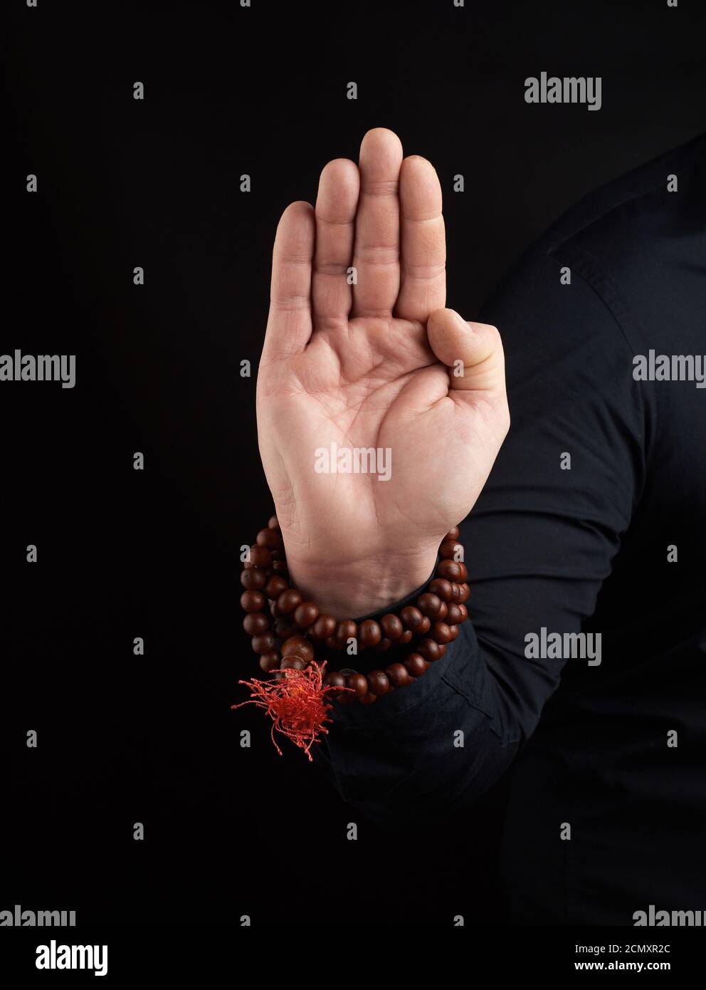 hand of an adult male shows abhayaprada mudra on a dark background ...