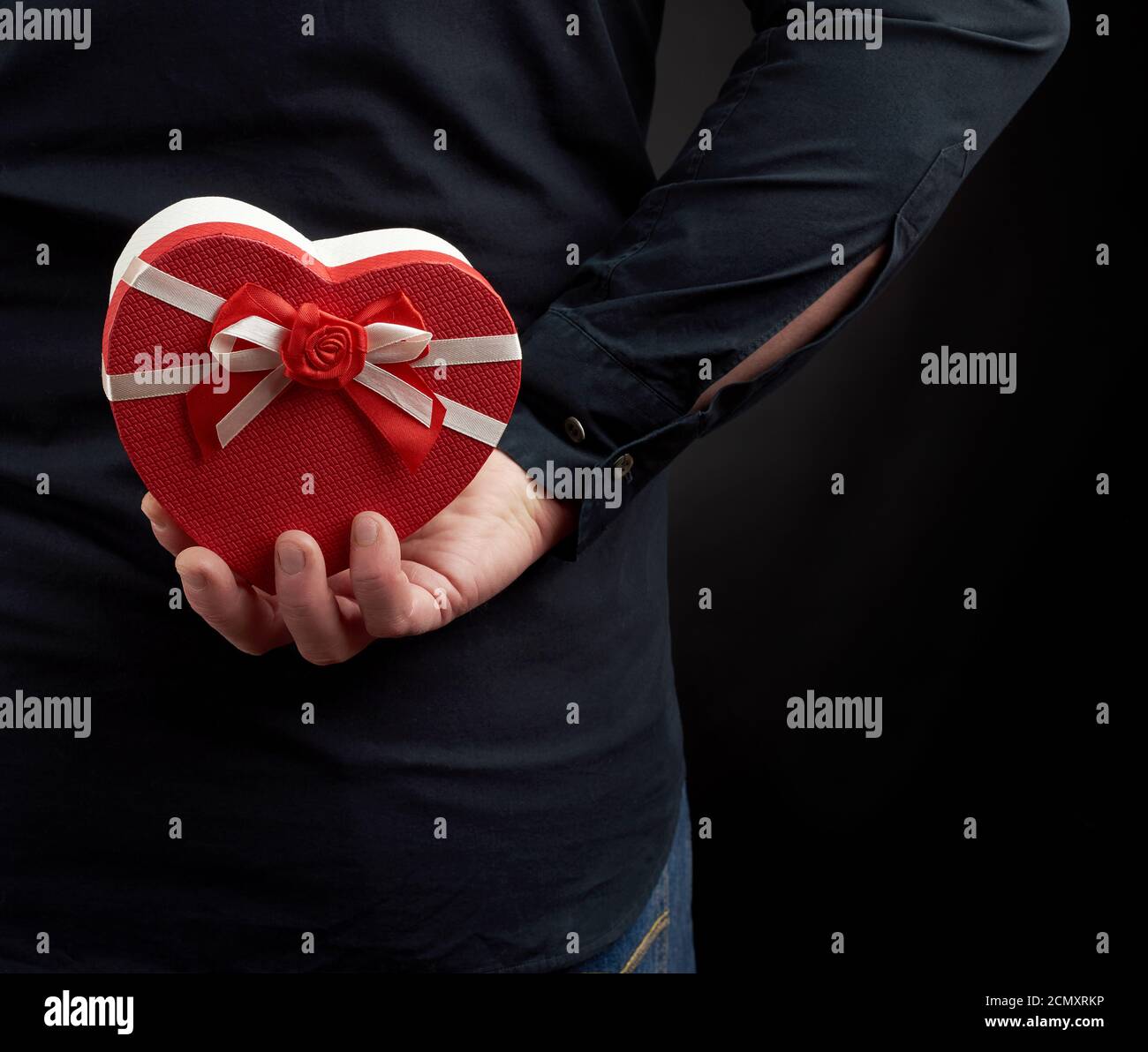 man’s hand holds a cardboard red box with a bow behind his back Stock ...