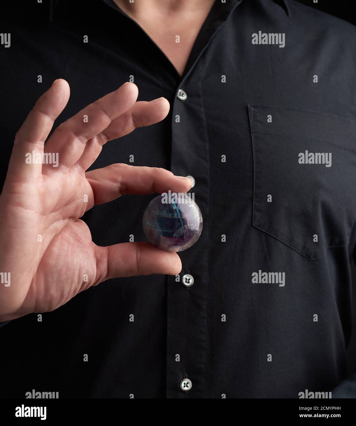 adult man in black clothes holds in his hands a glass magic ball ...