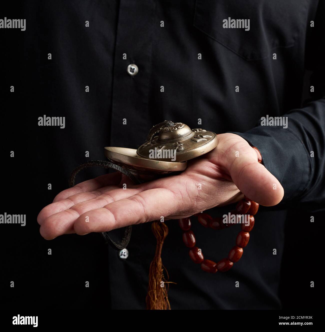 adult man in black clothes holds in his hands a pair of bronze Karatal ...