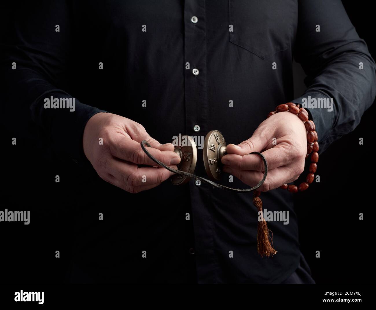 adult man in black clothes holds in his hands a pair of bronze Karatal ...