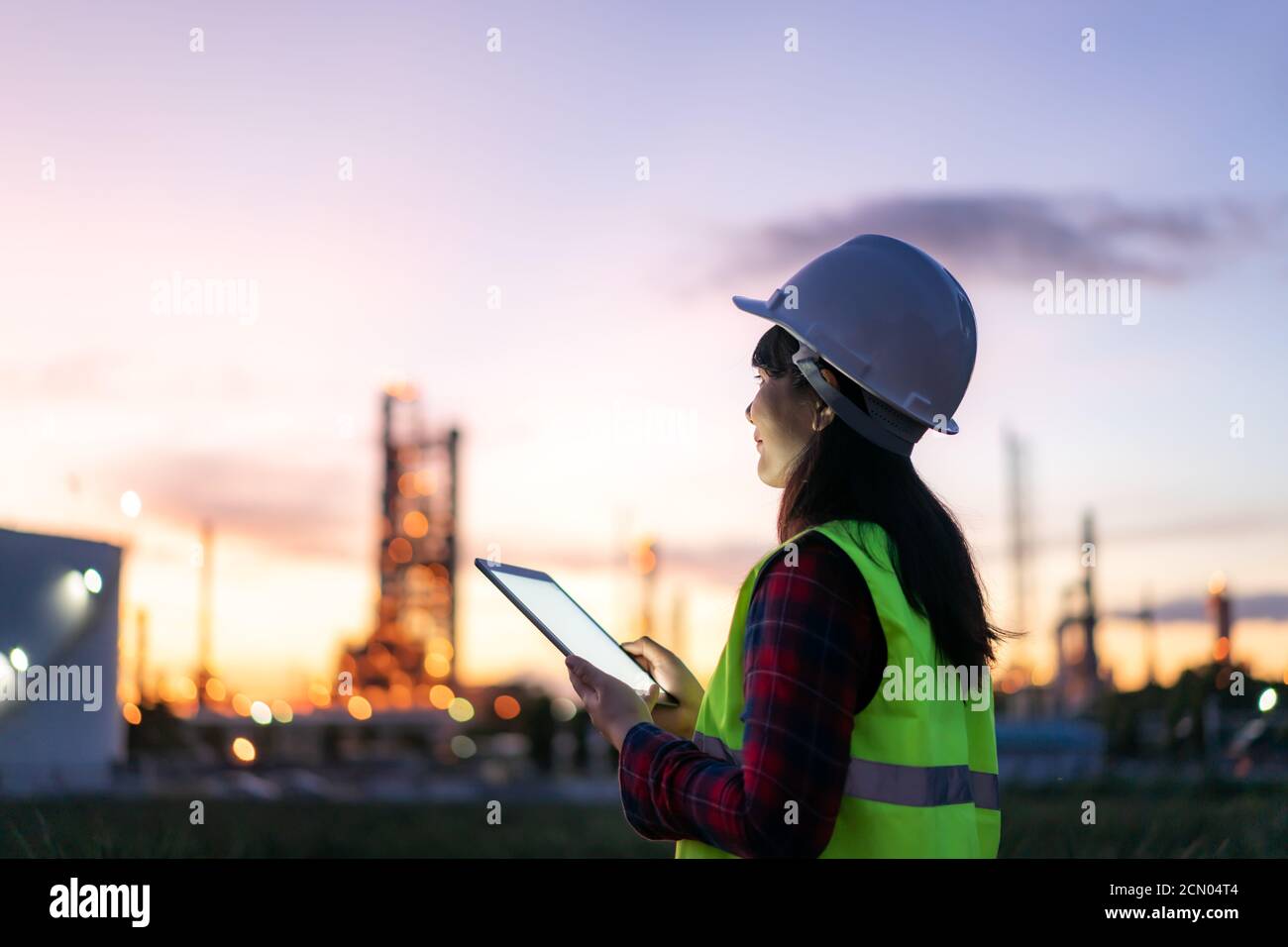 Asian woman petrochemical engineer working at night with digital tablet ...