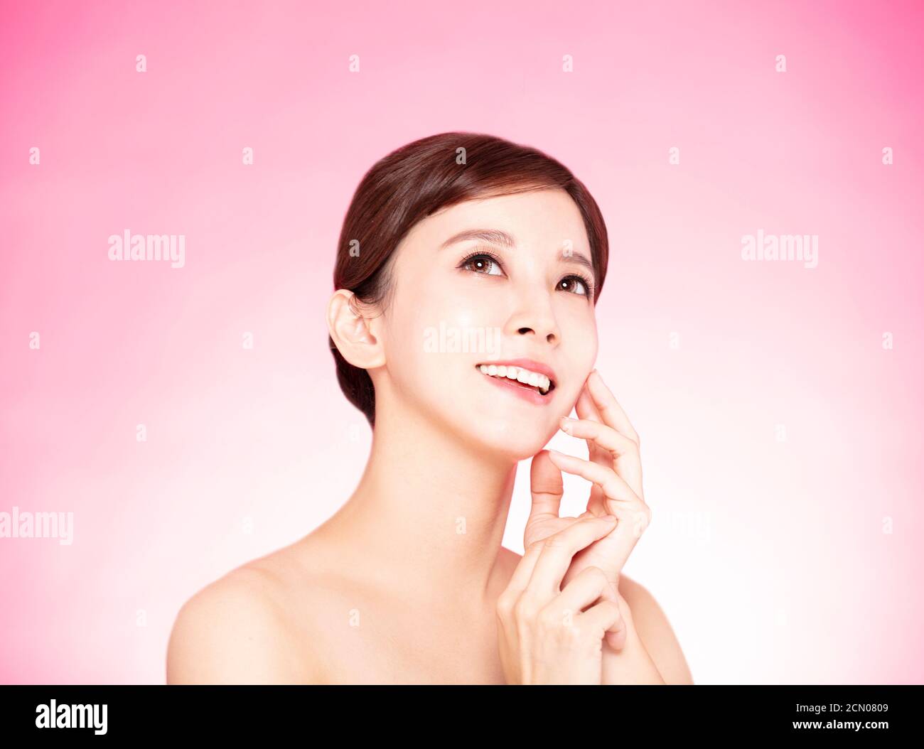 Beautiful young woman hand touching her face and looking up Stock Photo ...