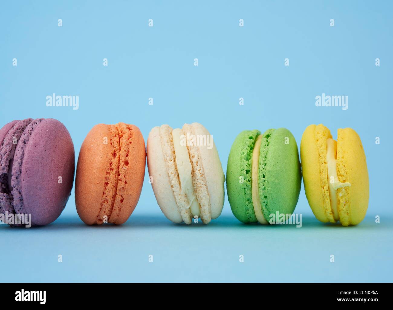 multi-colored round baked macarons cakes on a light blue background ...