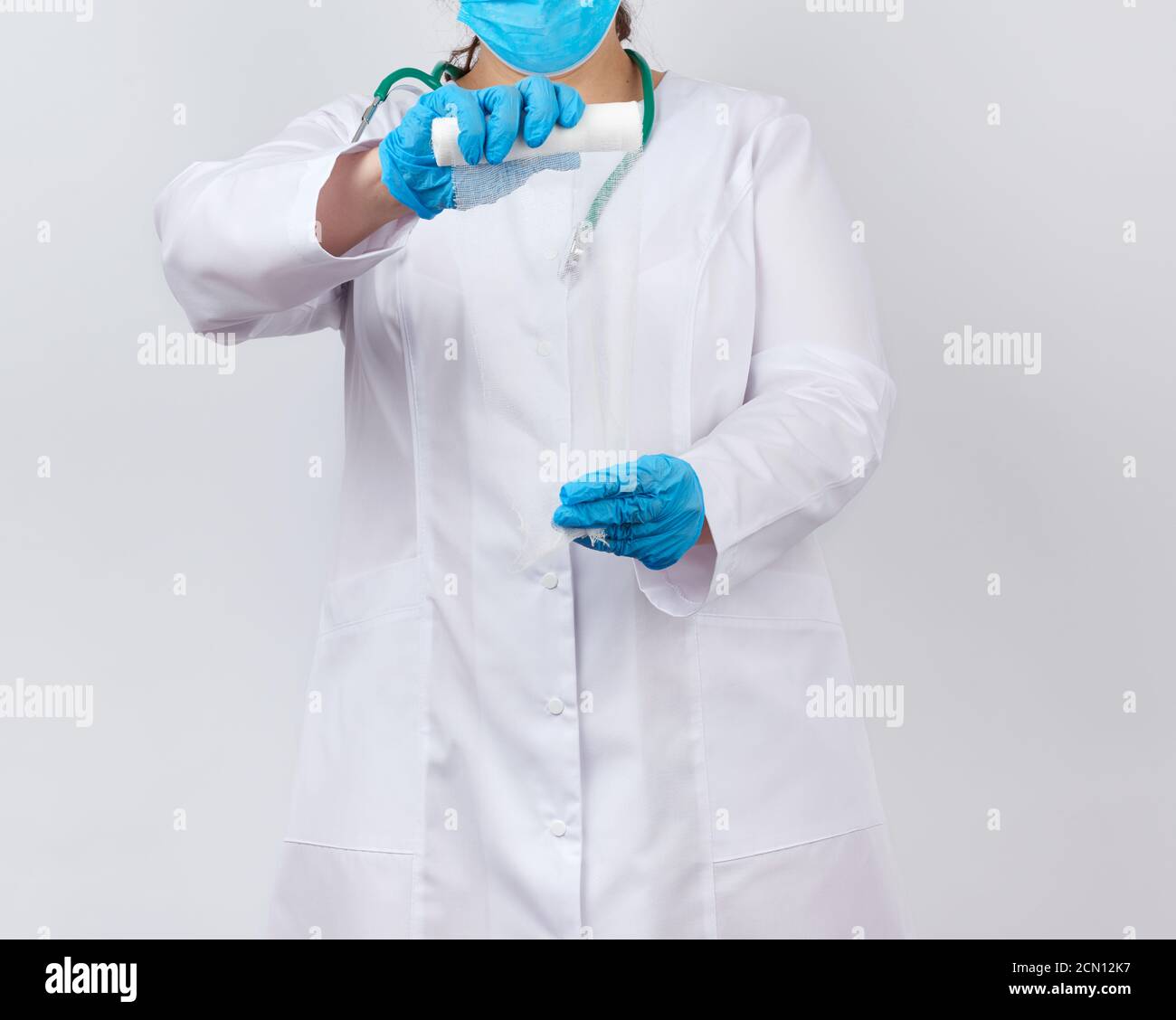 medic woman in white coat and mask holds a twisted gauze bandage for ...