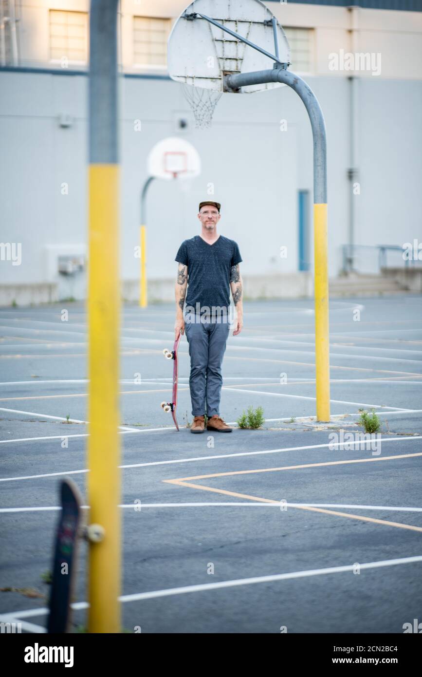 Full body portrait of adult male standing with skateboard Stock Photo ...