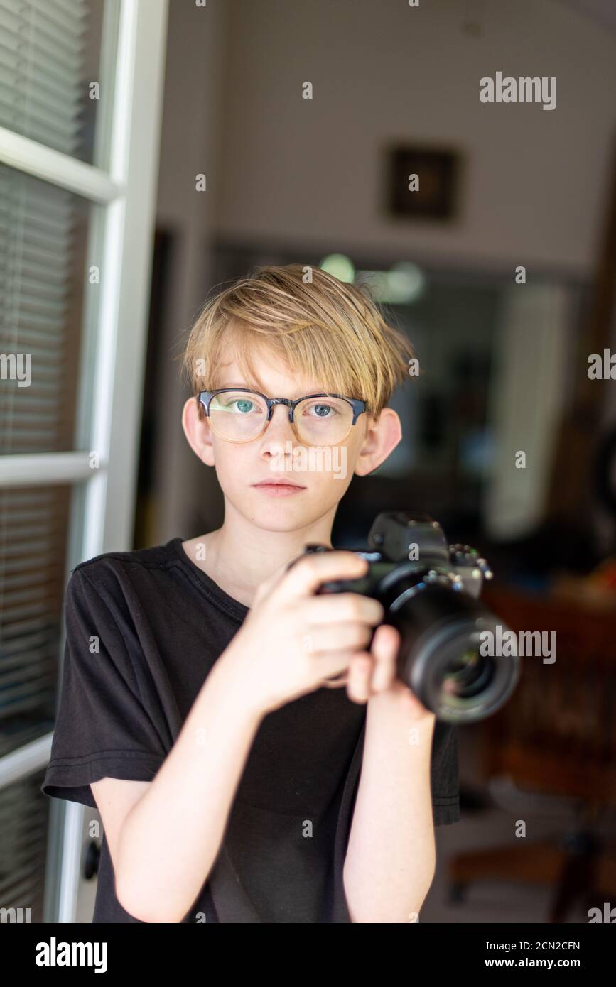 Tween making eye contact holding modern camera in doorway to home Stock ...