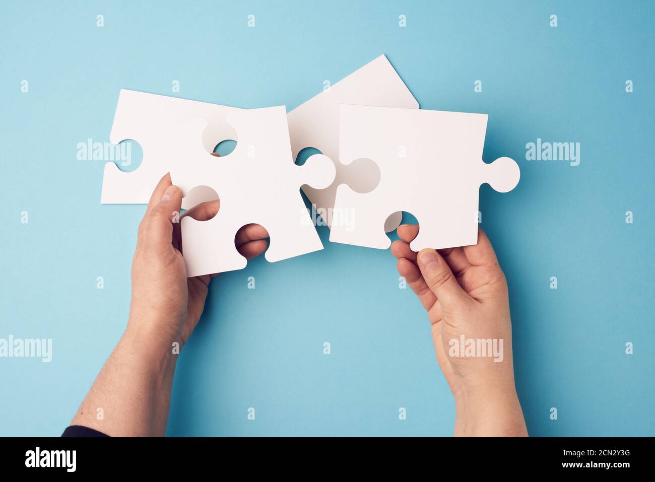 two female hands holding big paper white blank puzzles on a blue ...