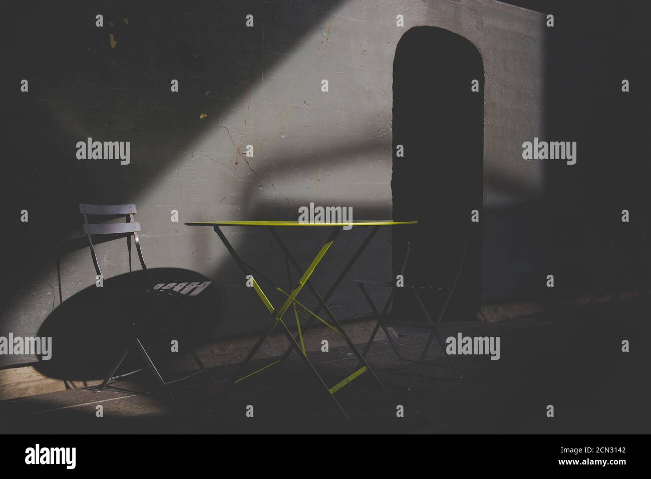 Empty table and chair bathed in light and shadows Stock Photo - Alamy