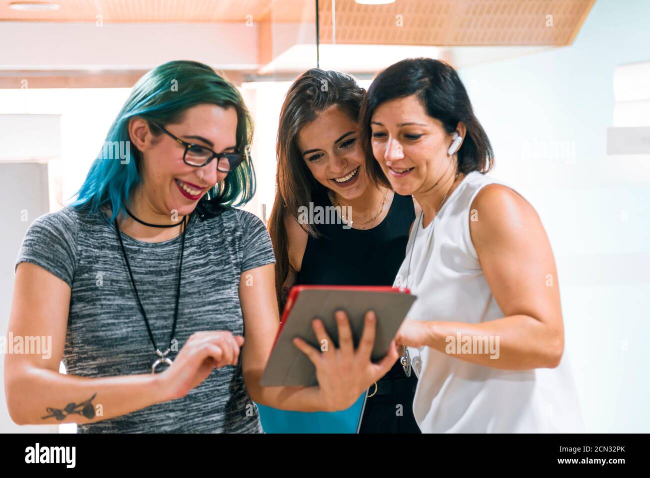 3 young women are looking at a tablet Stock Photo - Alamy