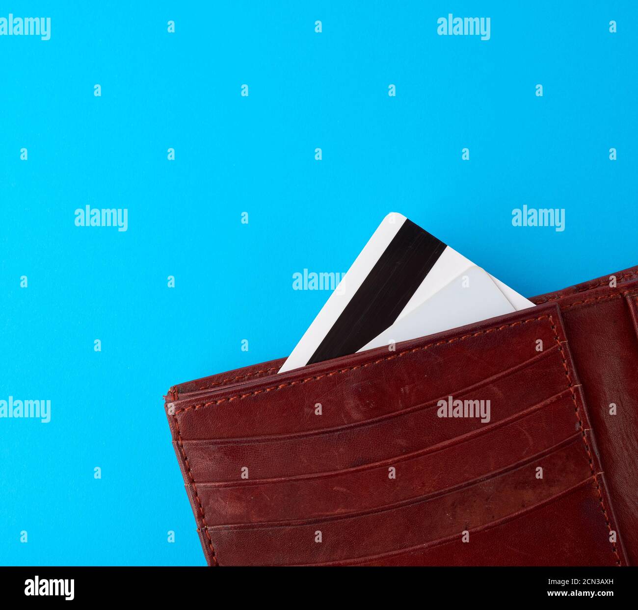 brown leather wallet, plastic bank cards stick out, blue background ...