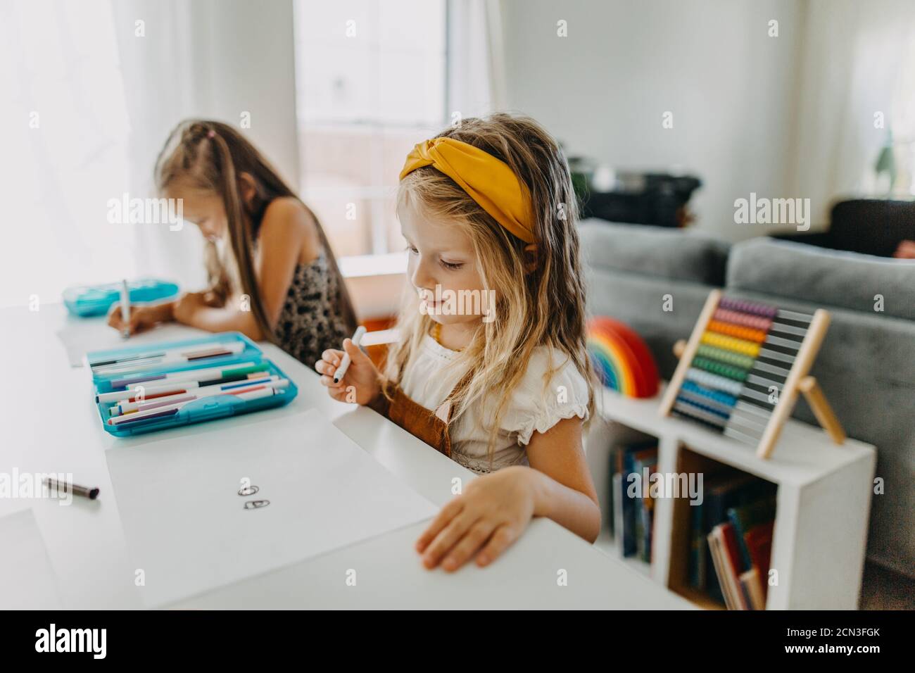Two girls drawing with colorful markers and paper and smiling at work ...