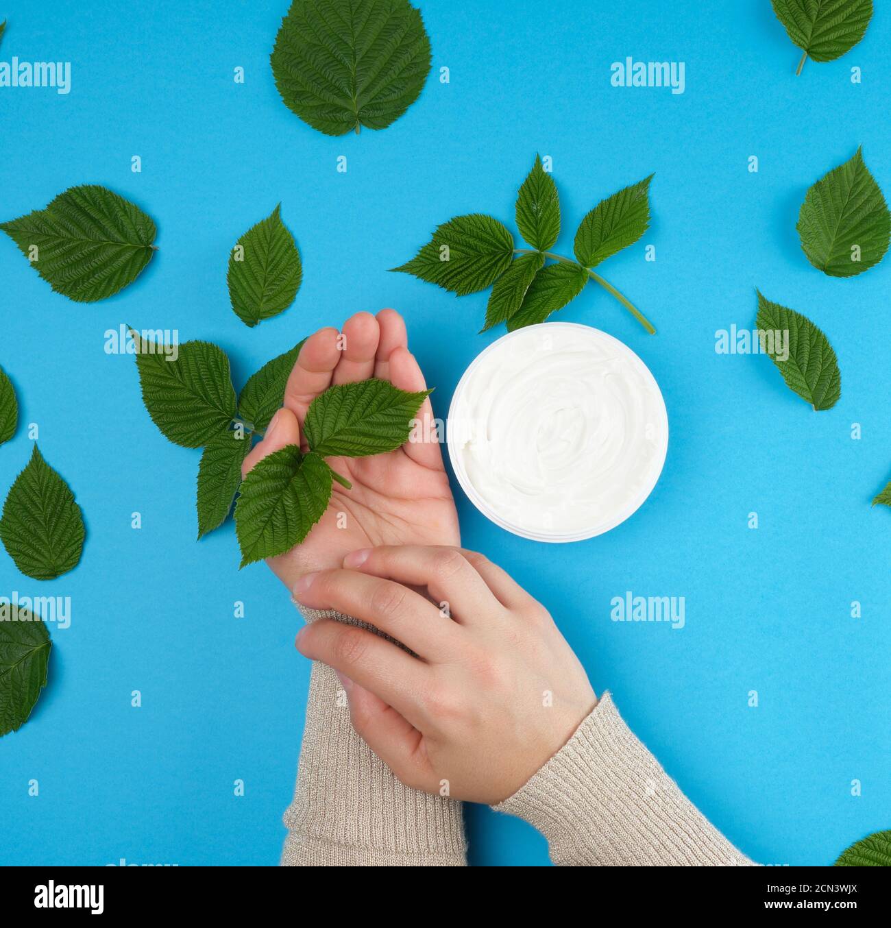 female hands of a young girl with smooth skin and round jar of cream ...
