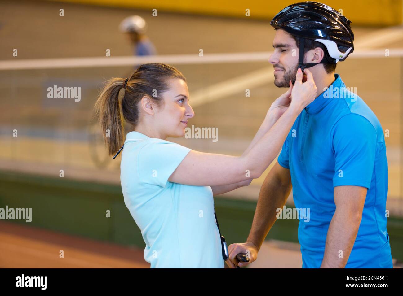 young woman helping her boyfriend to put on bicycle helmet Stock Photo ...