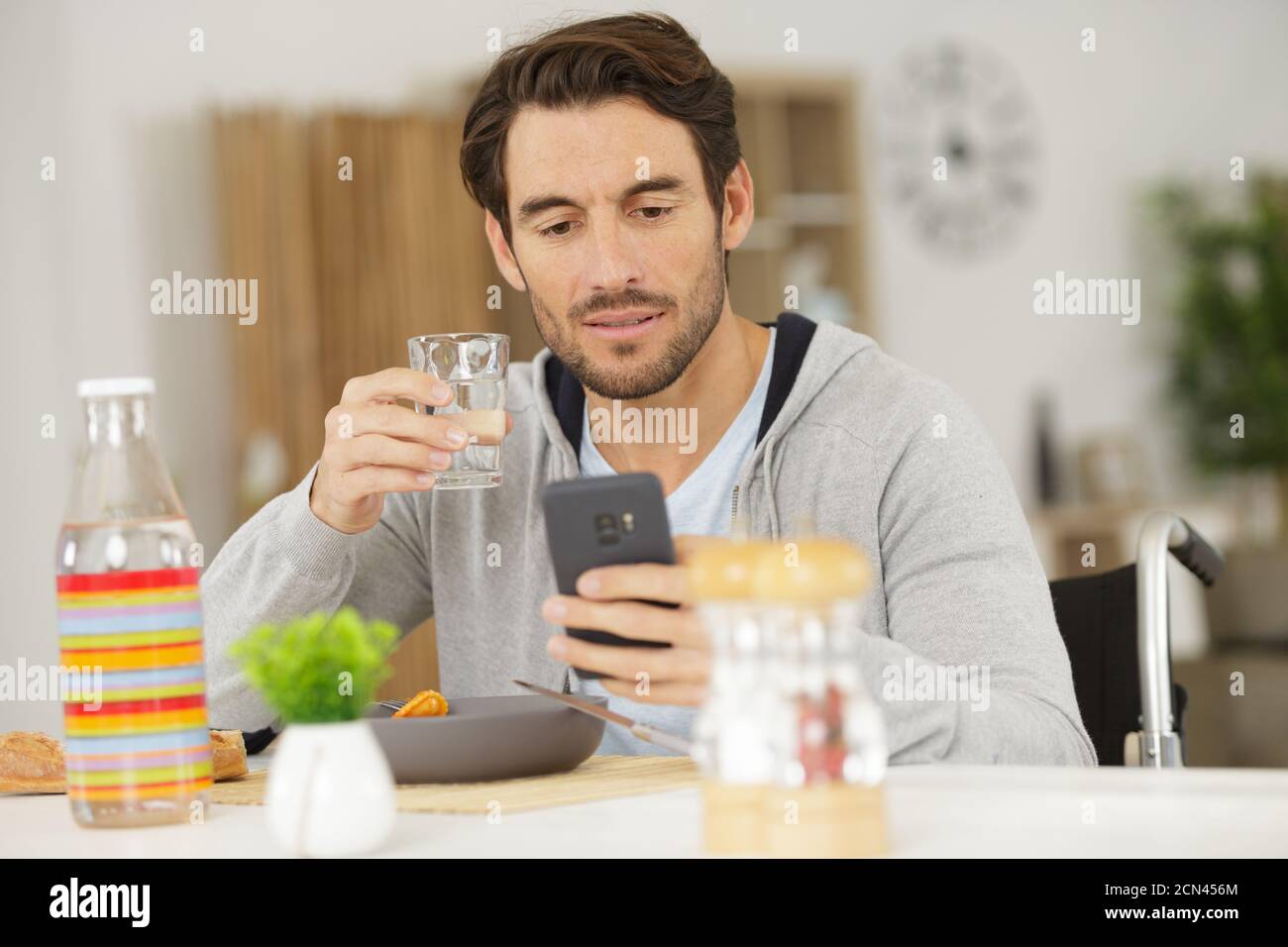 handicapped man looking at smartphone while eating his meal Stock Photo ...