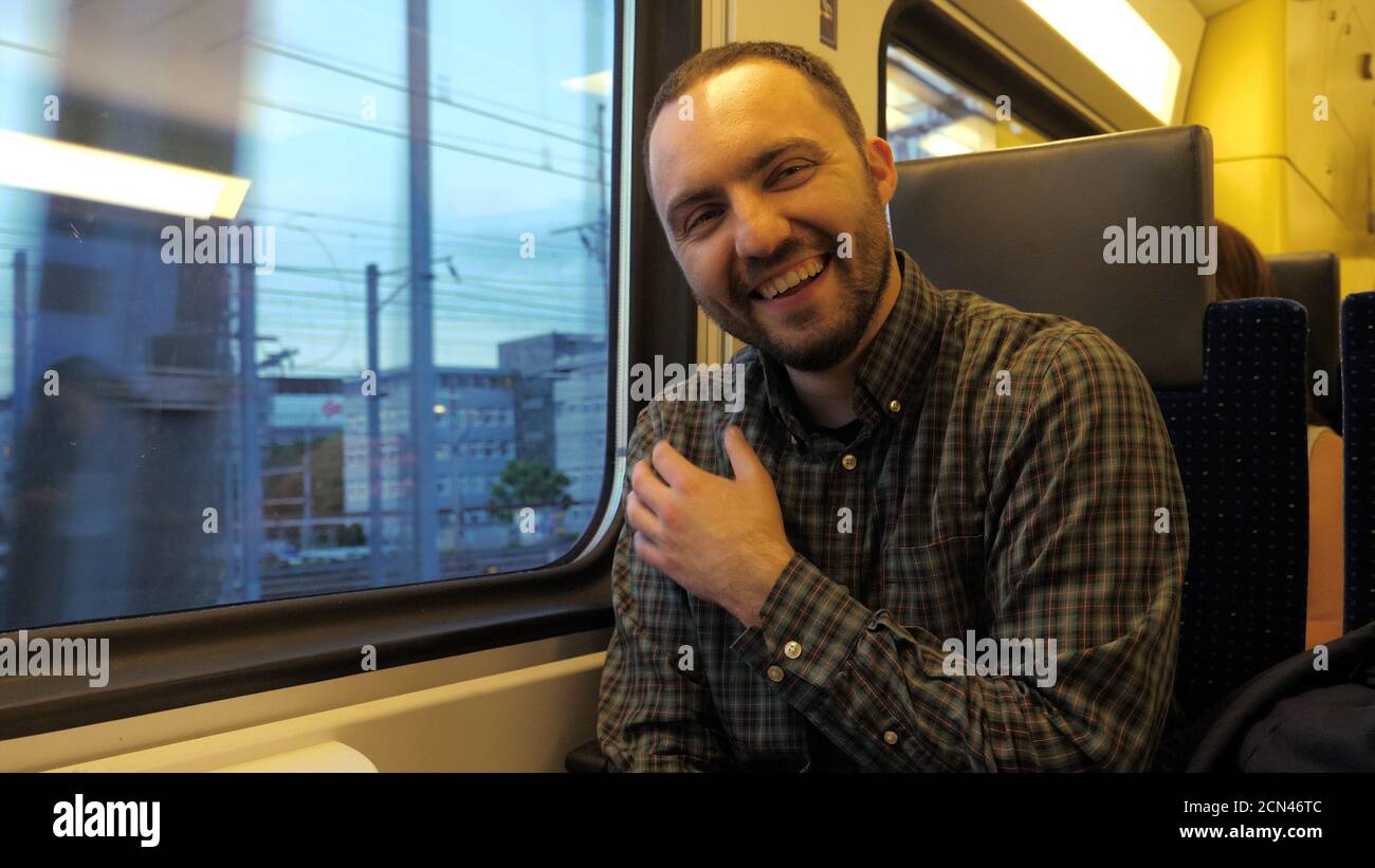 Cheerful man telling a joke and laughing in a train Stock Photo - Alamy