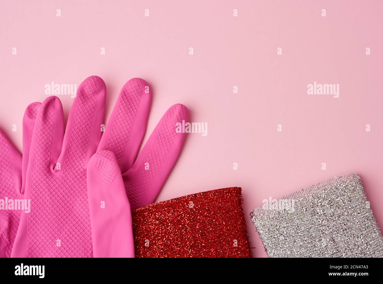 multi-colored kitchen sponge, rubber pink gloves on a pink background ...