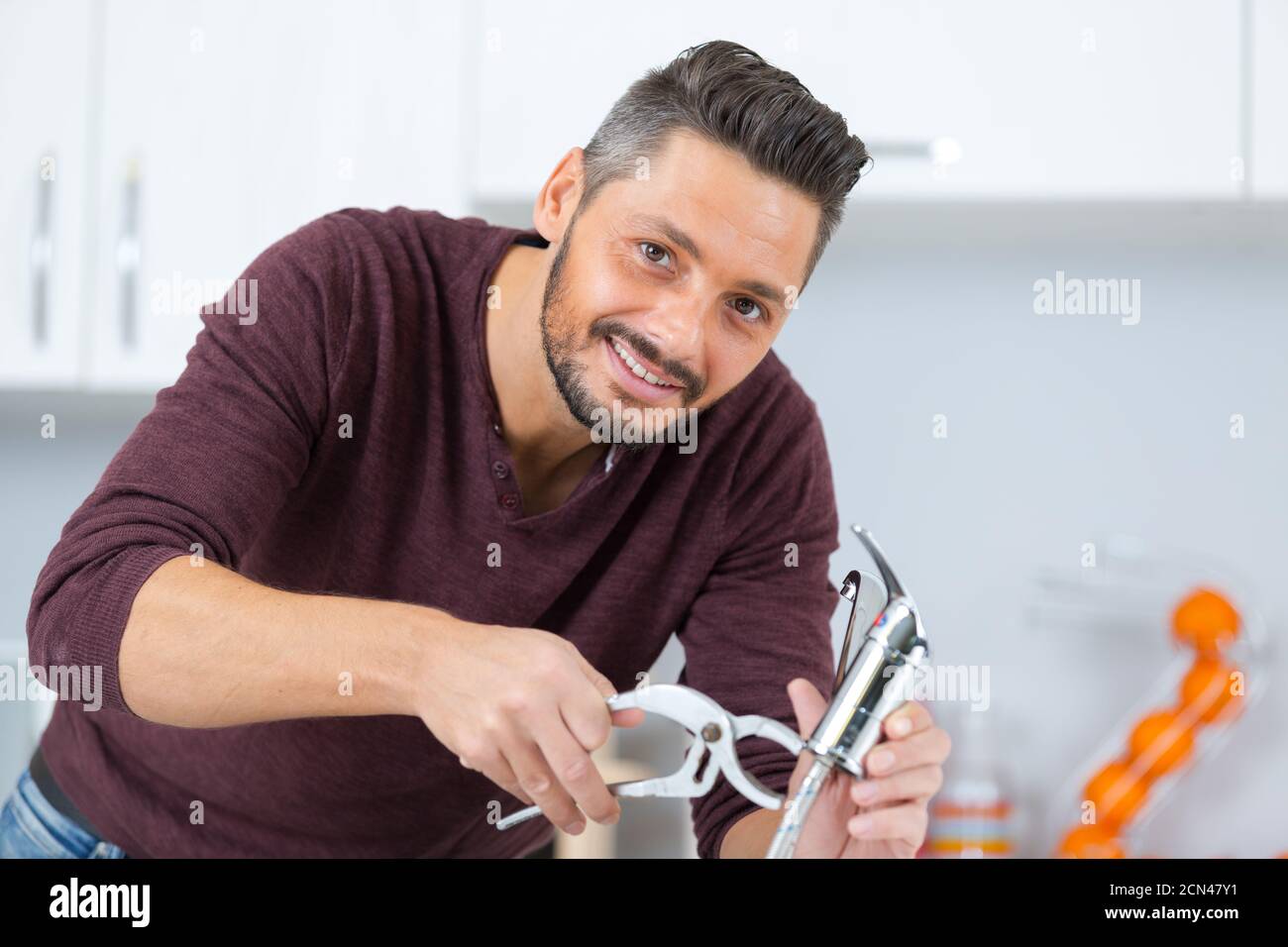 happy man fixing tap with tool in the kitchen Stock Photo - Alamy